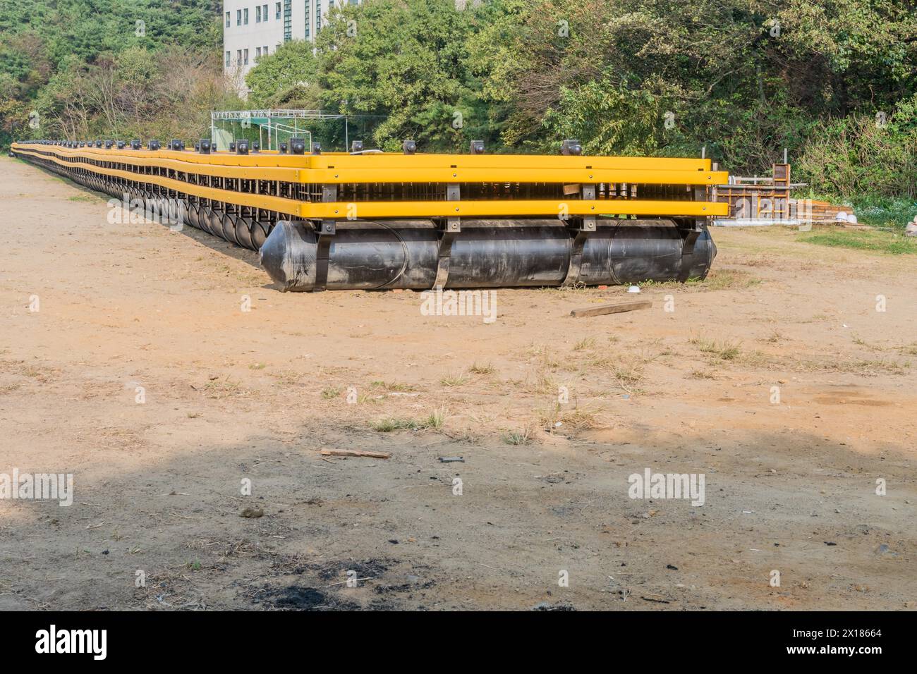 Large floating pier sitting on sandy ground with trees in background in ...