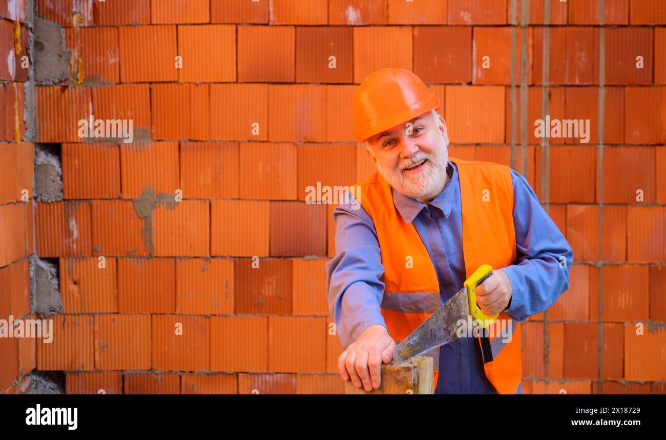 Carpentry workshop. Carpenter with hand saw cutting wooden board ...
