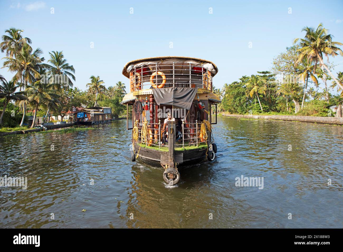 Traditional houseboat on a canal in the canal system of the backwaters ...