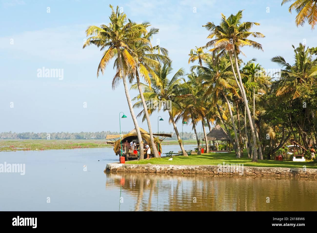 Palm trees and traditional houseboat on the shores of Lake Vembanad ...