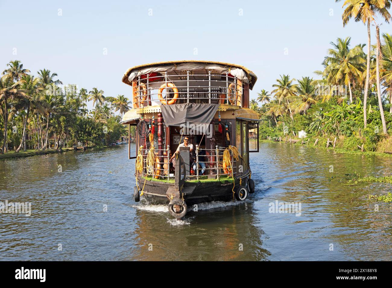 Traditional houseboat on a canal in the canal system of the backwaters ...