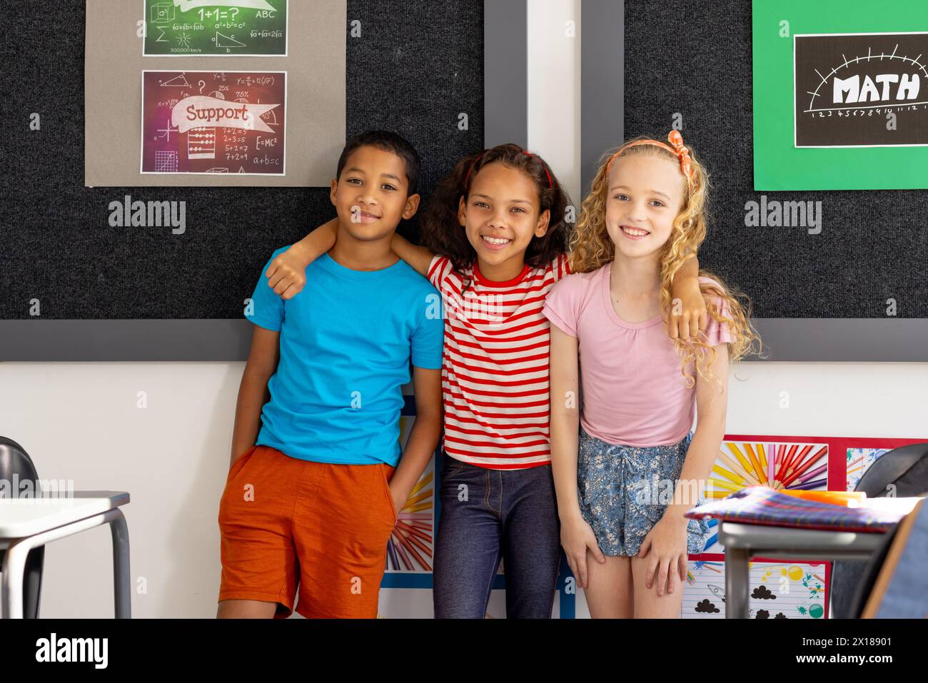 In school, three young students posing together in the classroom, two ...