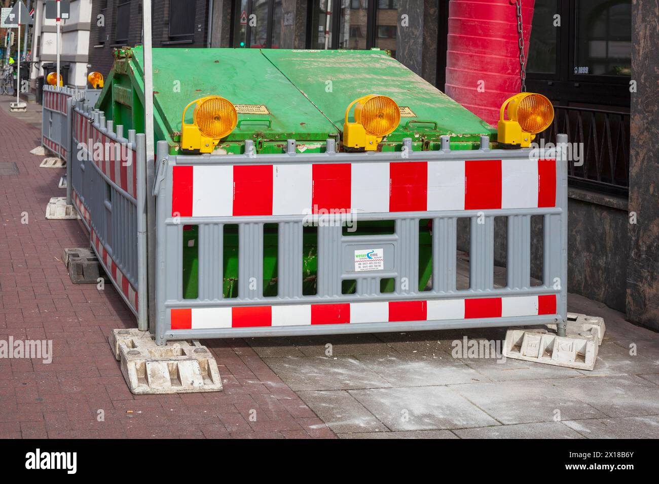 Construction site with barrier and waste container or skip for building ...