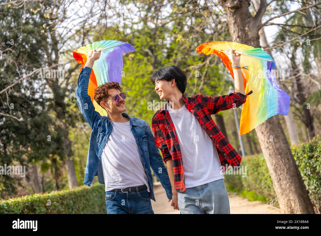 Happy multiracial gay couple walking holding hands and waving LGBT ...