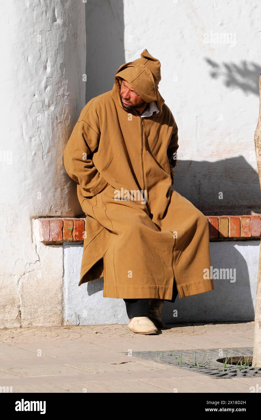 Chefchaouen, Man in traditional brown clothes sitting alone in the ...