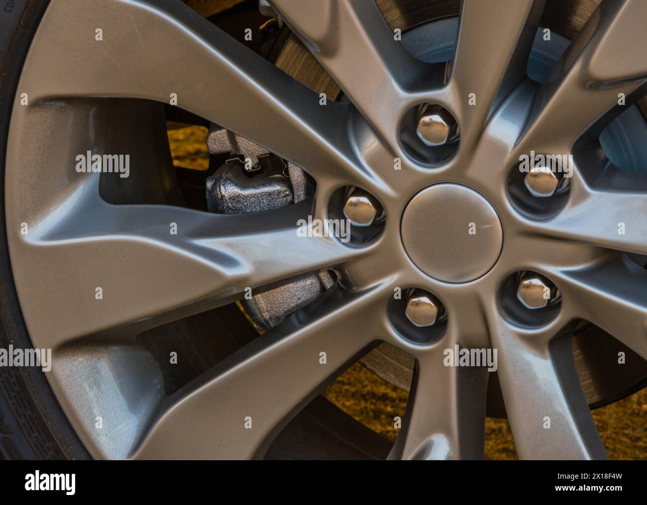 Closeup of shinny chrome aluminum wheel with lug nuts and view of metal ...