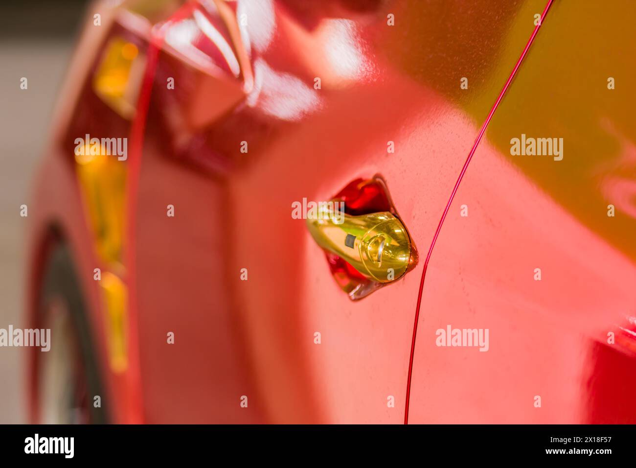 Closeup of gold colored door handle on side of red car reflecting ...
