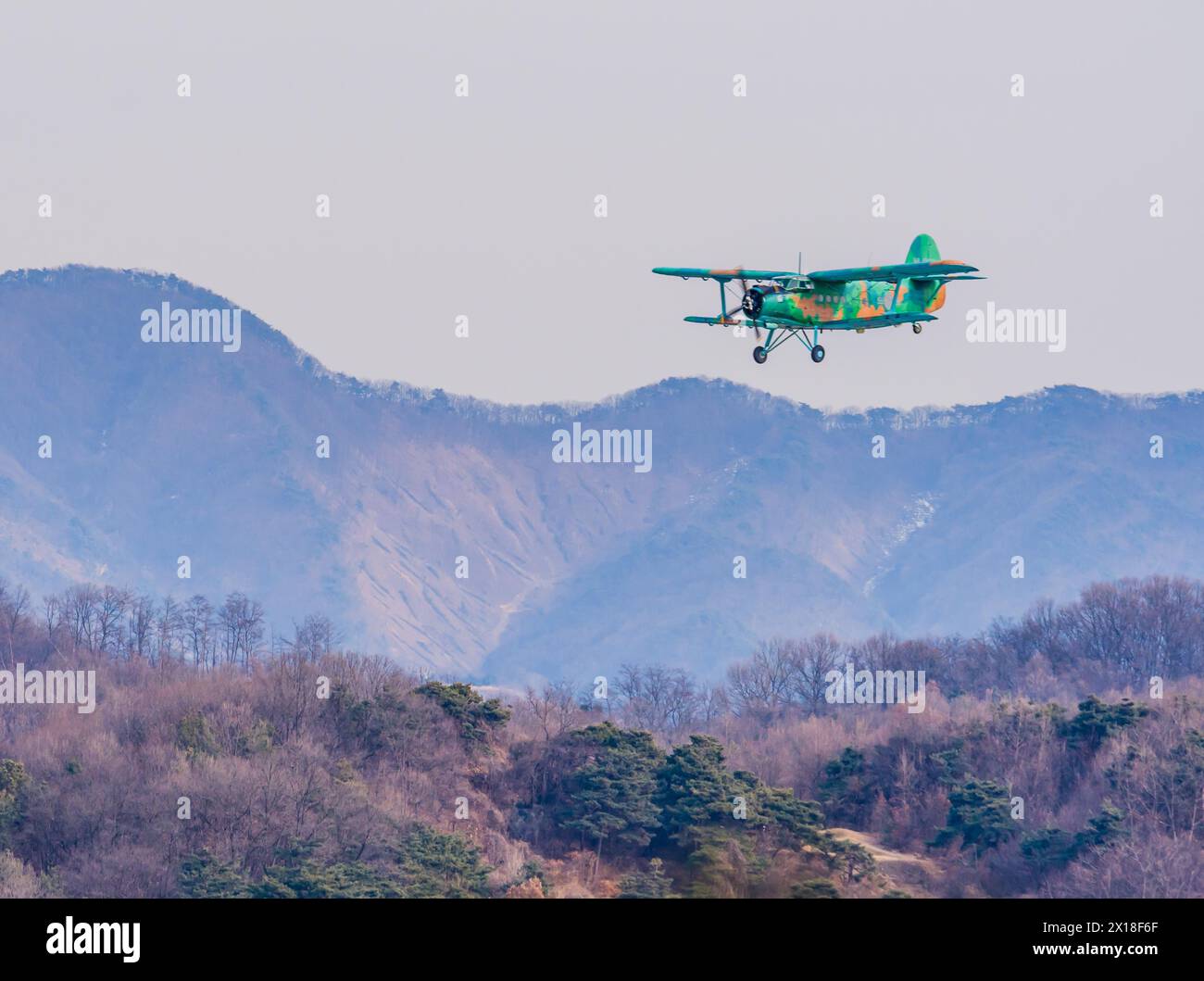 ROK military biplane training aircraft flying over mountainous region ...