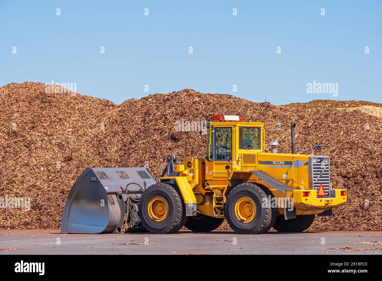 Loading machine at large piles of wood chips at a loading area Stock ...