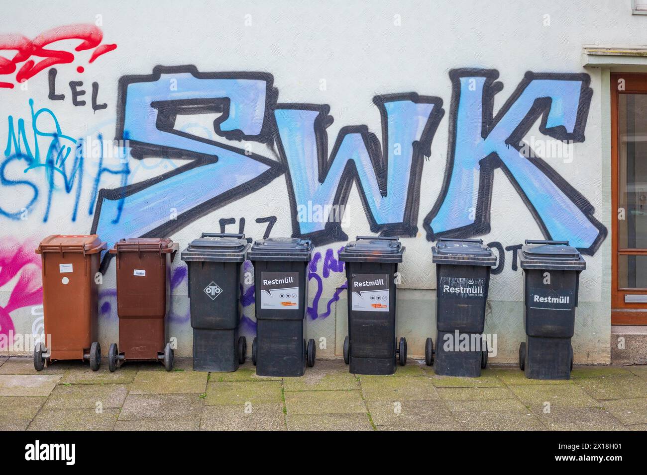 Rubbish bins in front of a graffiti-covered house wall, Bremen, Germany ...