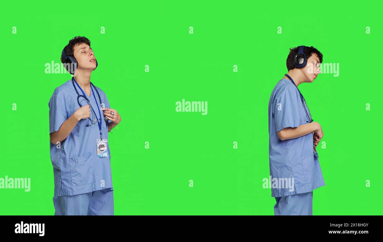 Joyful nurse singing and dancing with wireless headphones on, listening ...