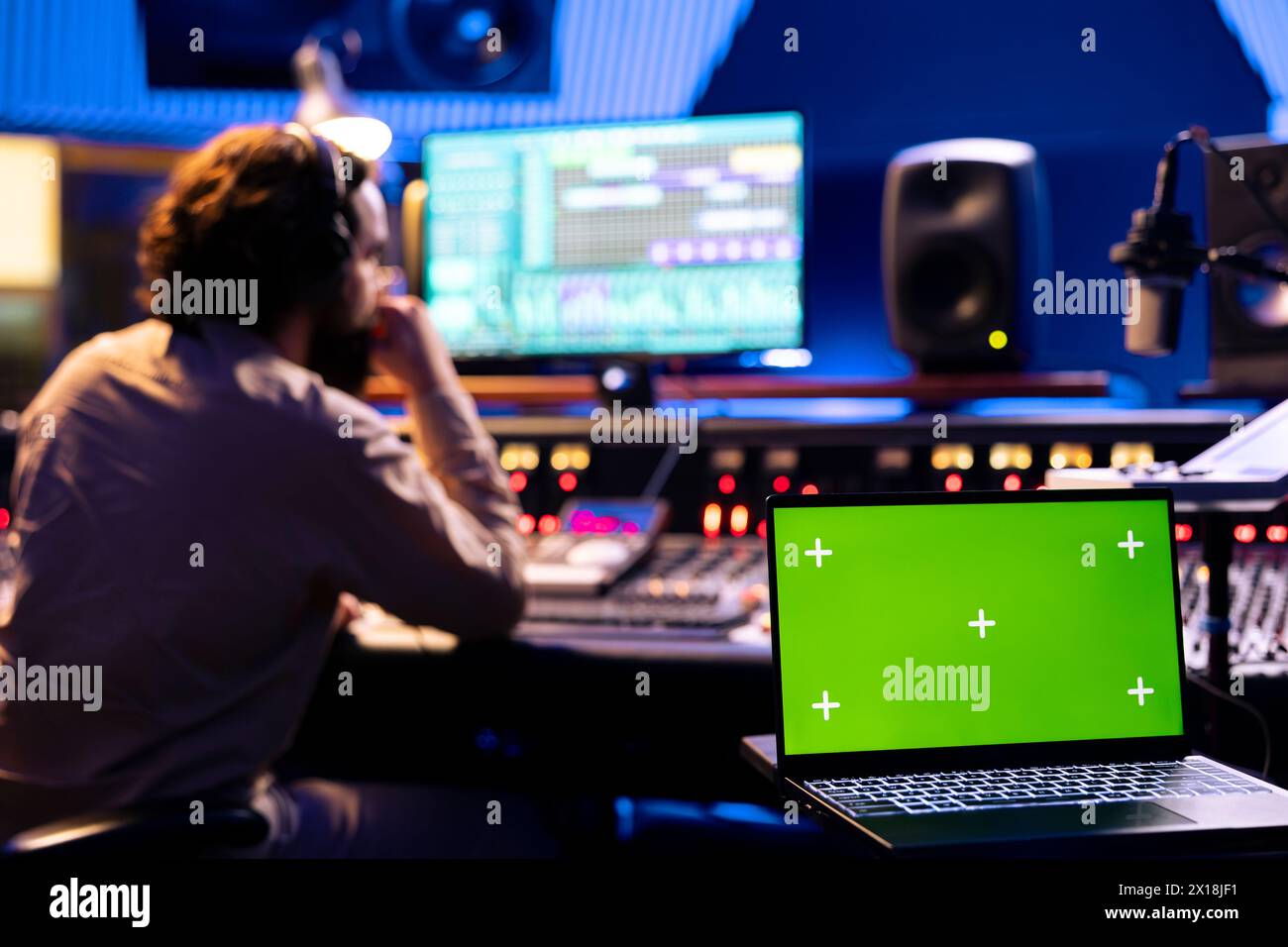 Male technician working on editing tracks next to greenscreen on laptop ...