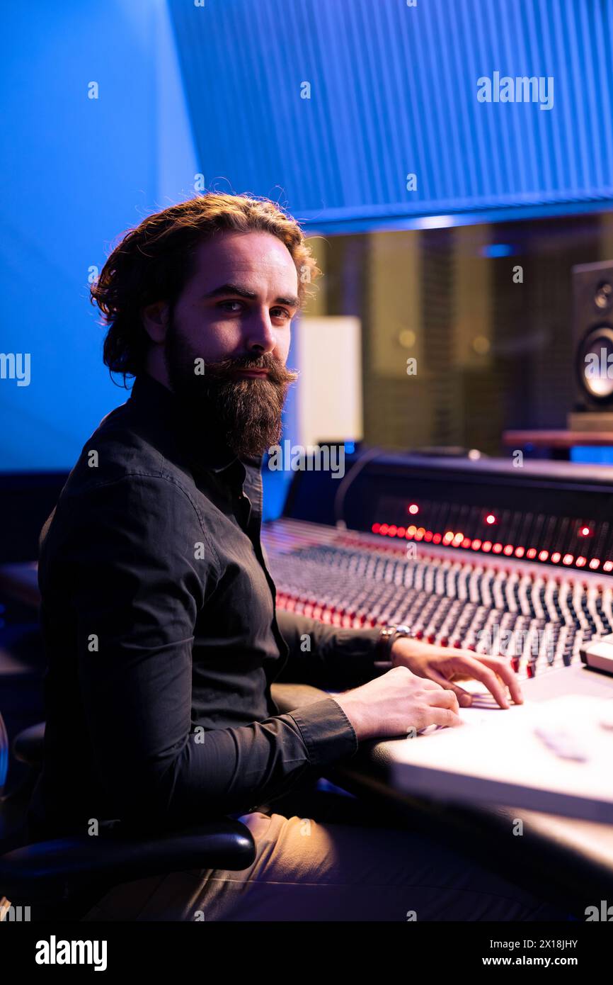Portrait of sound engineer working with audio console and digital ...