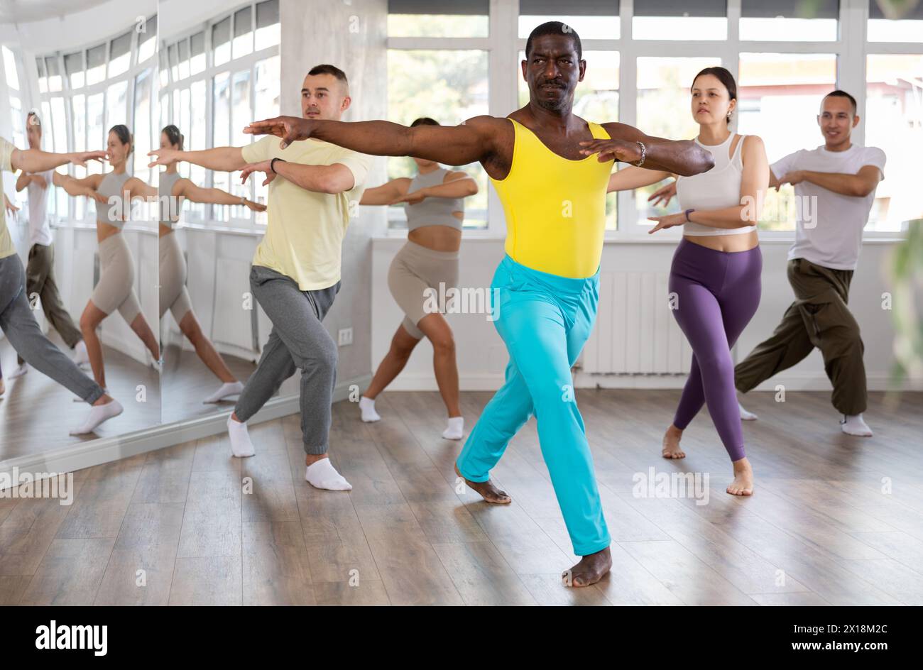 Enthusiastic black man energizing group during dance fitness class ...