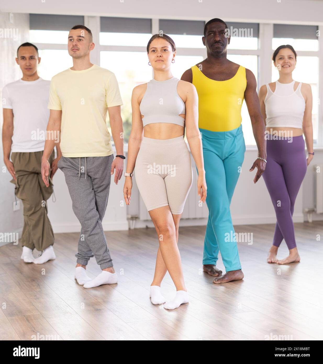 Multinational group of young people stand in row holding hands ...