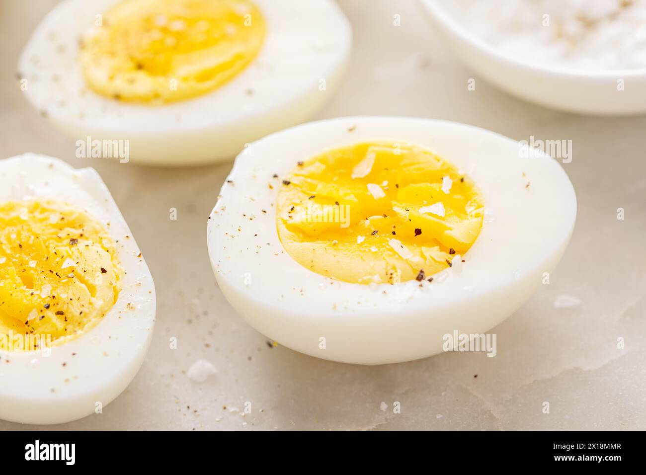 Hard boiled eggs peeled and cut in half with salt and pepper Stock ...