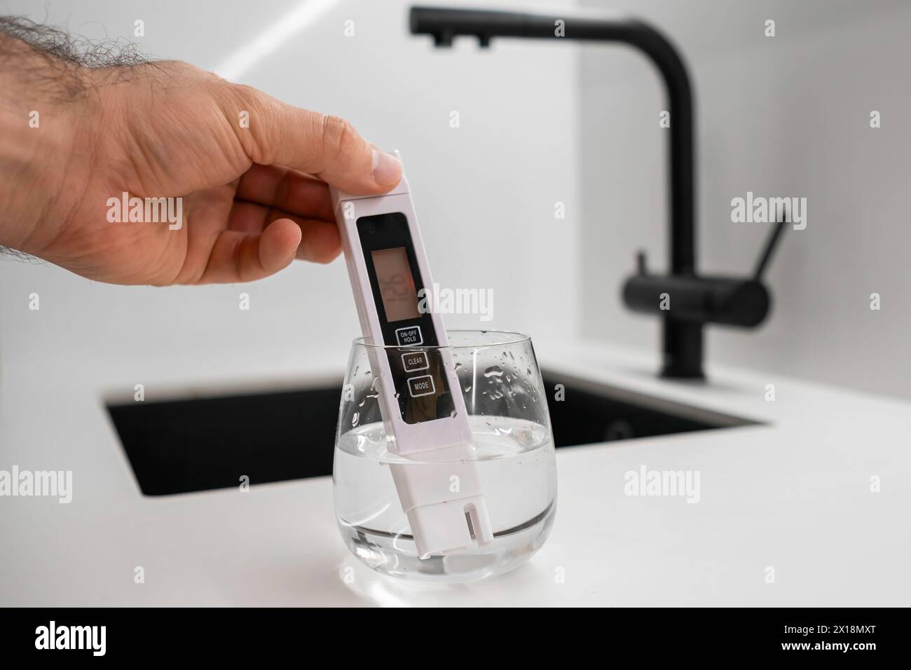 Man hand immerses conductometer in a beaker of water to check purity in ...
