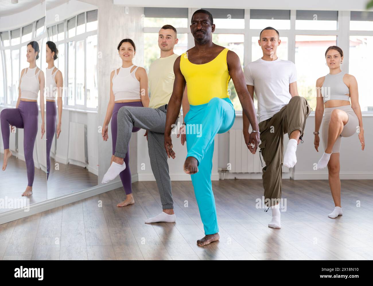 Multinational group of young people stand in row holding hands ...