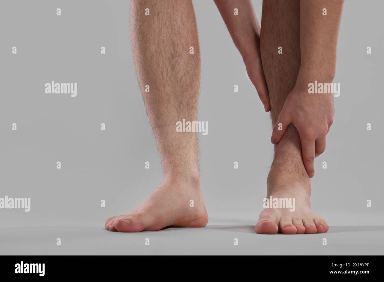 Man suffering from leg pain on grey background, closeup Stock Photo - Alamy