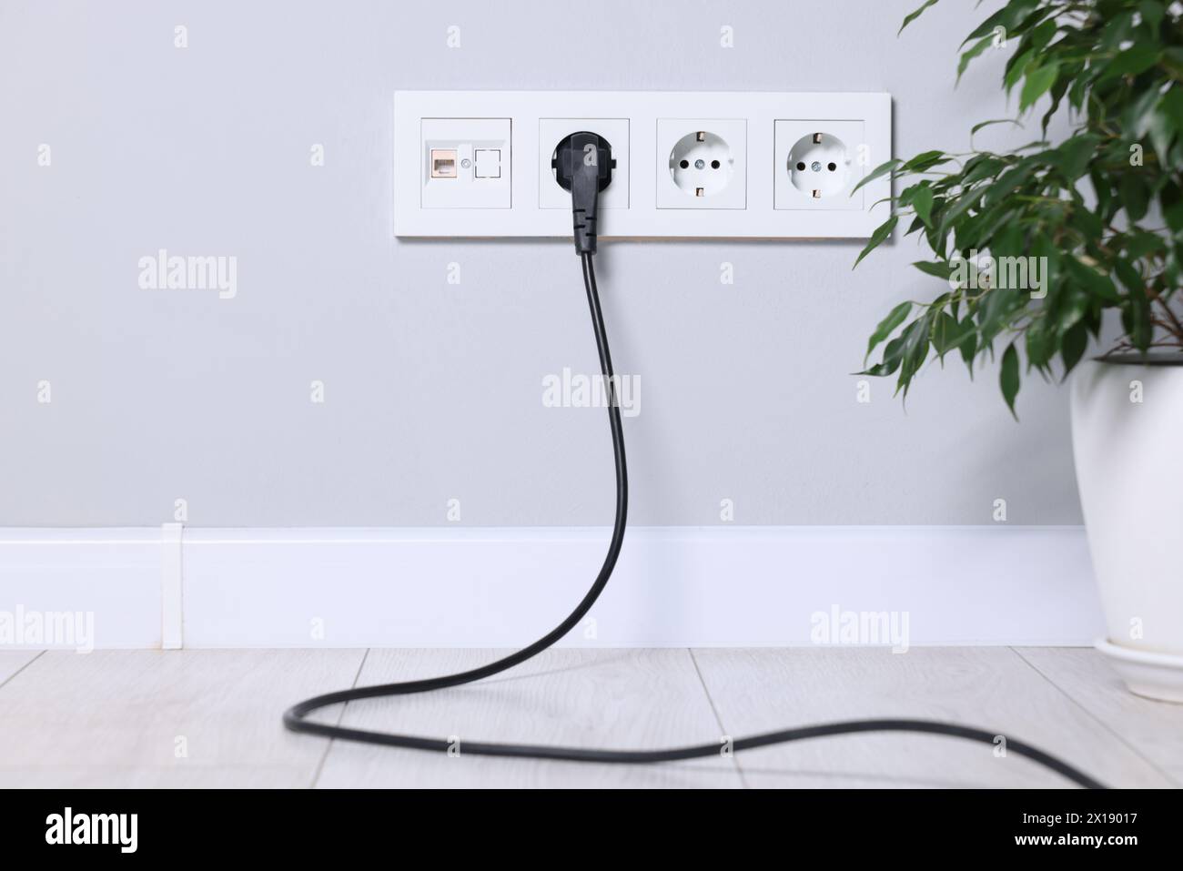 Power sockets and electric plug on grey wall Stock Photo - Alamy
