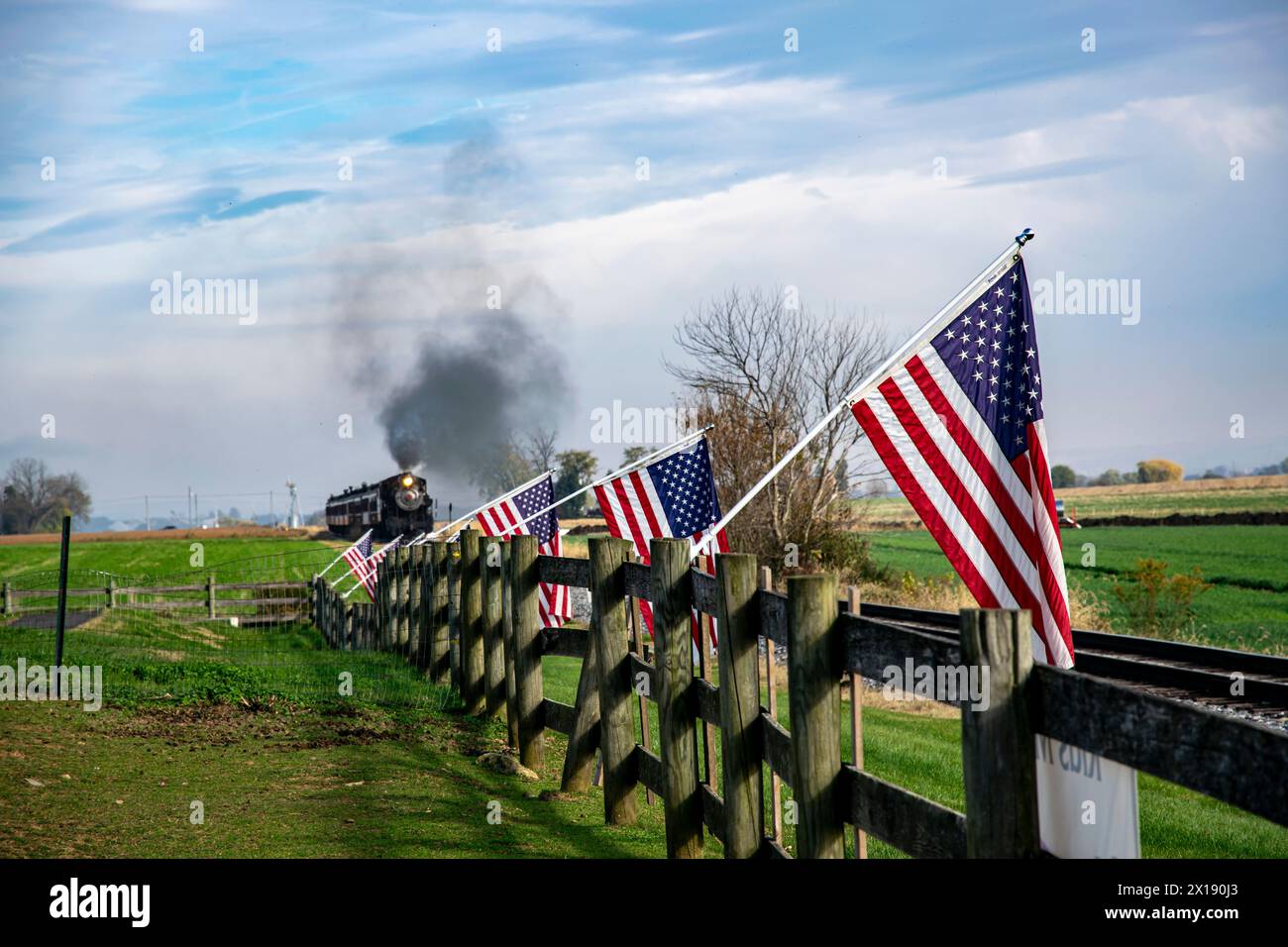 A vintage steam train chugs along the countryside, flanked by American ...
