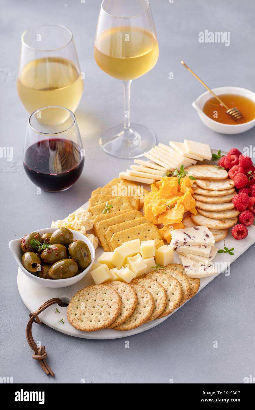 Cheese and snacks board with cheddar, swiss cheese, olives and crackers ...