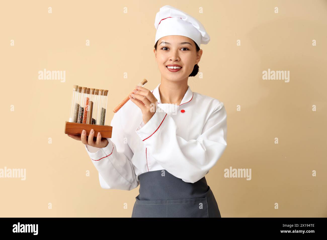 Female Asian chef with spices on beige background Stock Photo - Alamy