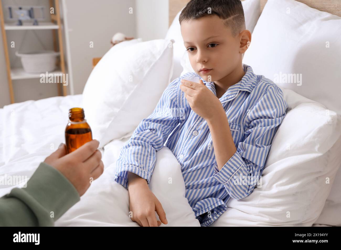 Ill little boy with his mother taking cough syrup in bedroom Stock ...
