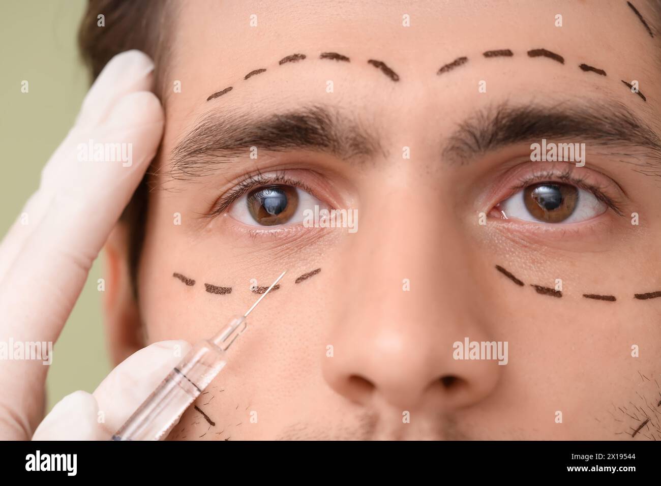 Young man with marked face receiving injection on green background ...