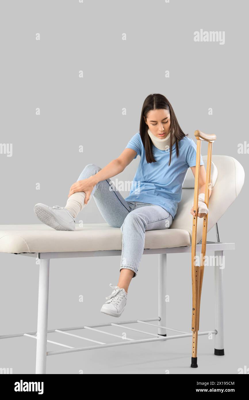 Injured young woman after accident with crutch on couch against light ...