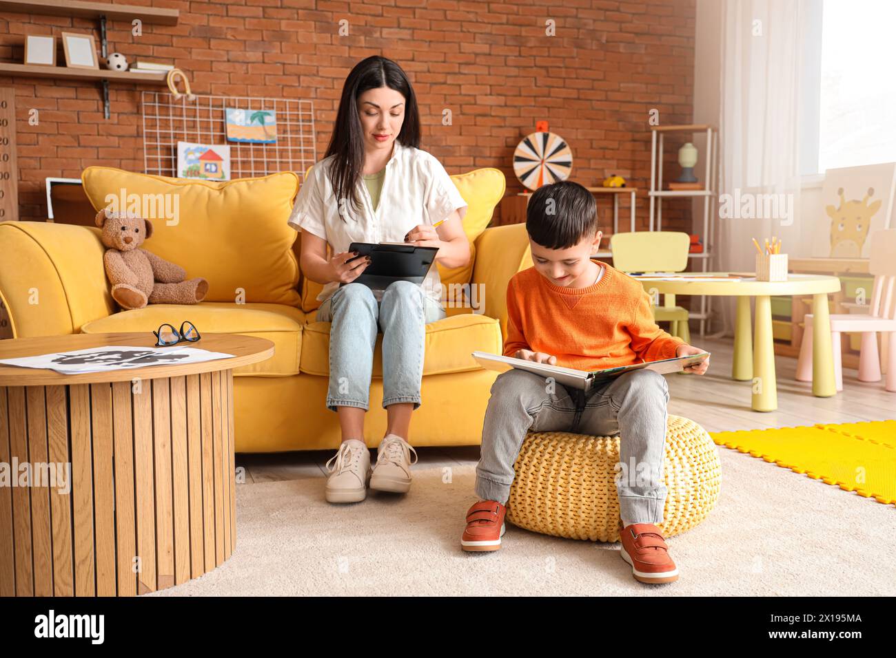 Female psychologist with little boy reading book in office Stock Photo ...