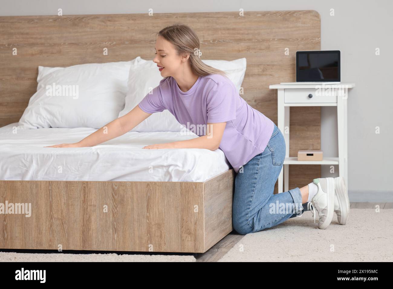 Pretty young woman making bed in modern bedroom Stock Photo - Alamy