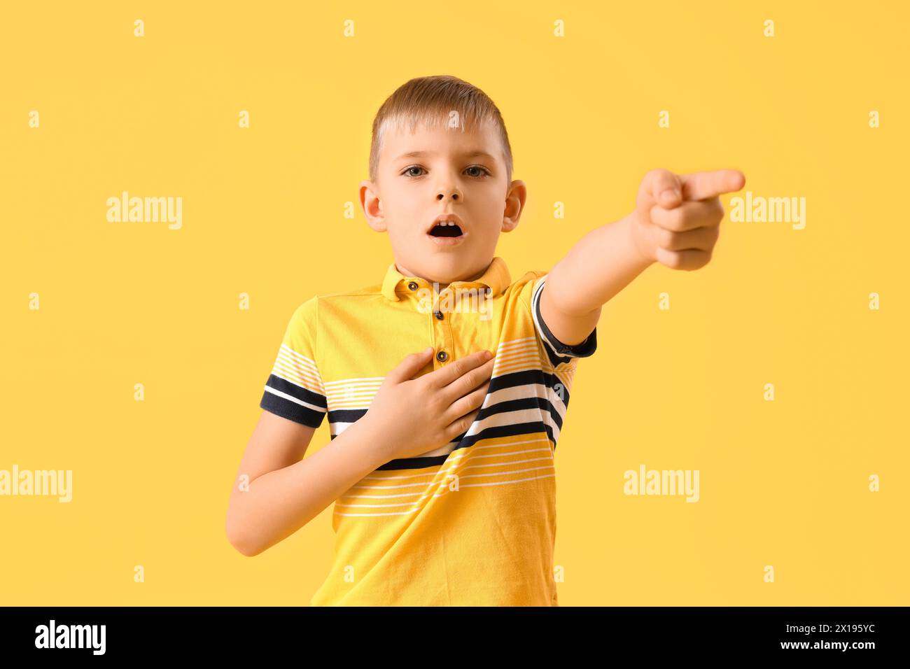 Shocked little boy pointing at something on yellow background Stock ...