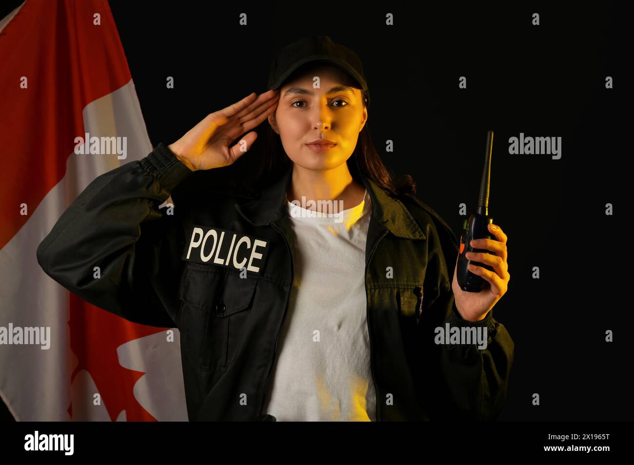Saluting female police officer with walkie-talkie and flag of Canada on ...