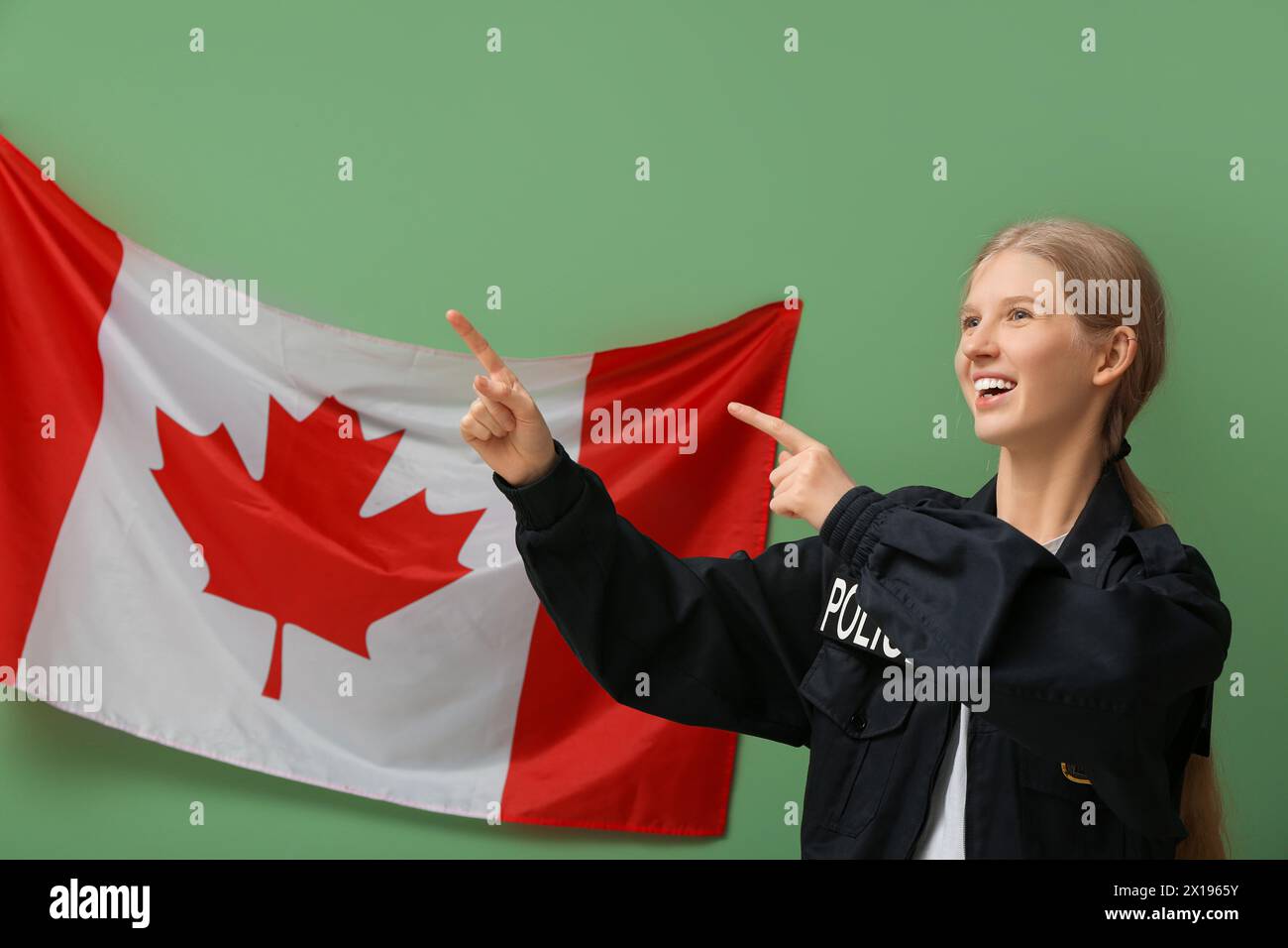 Female police officer pointing at something and flag of Canada on green ...