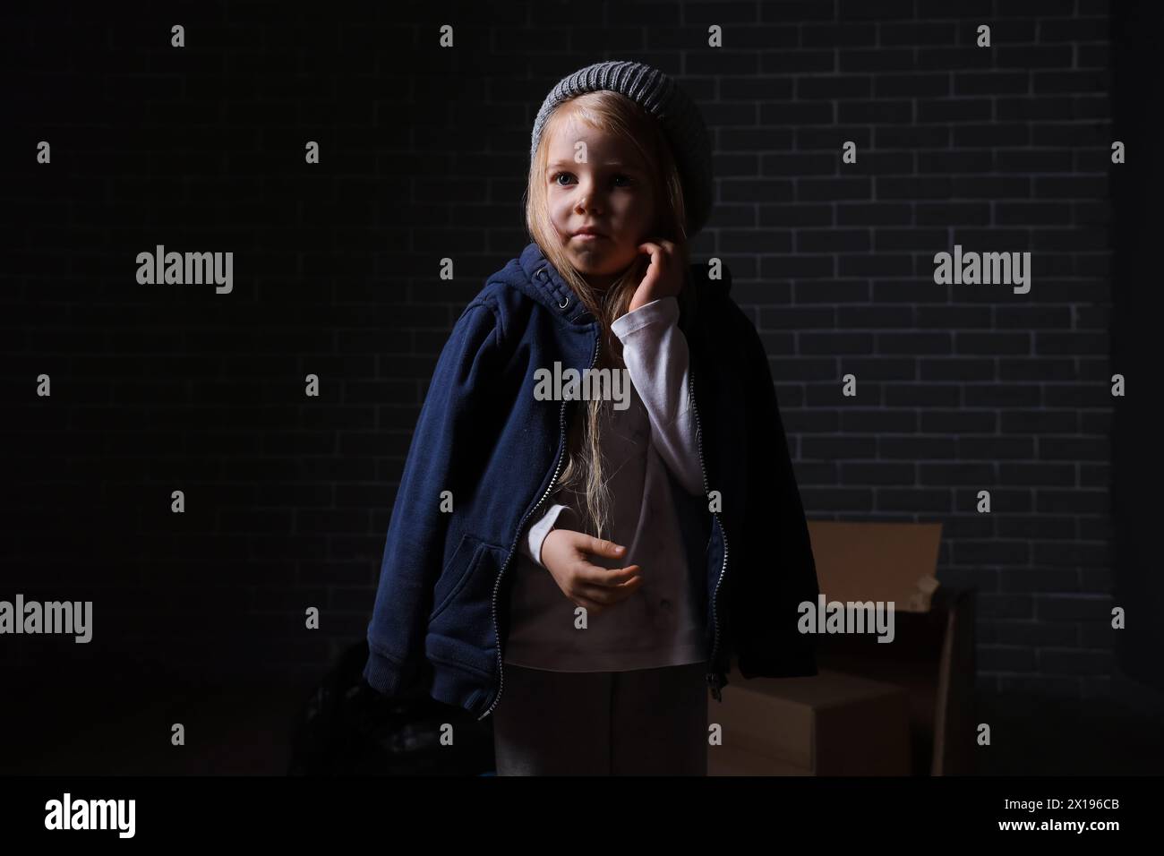 Homeless little girl against grey brick wall Stock Photo - Alamy