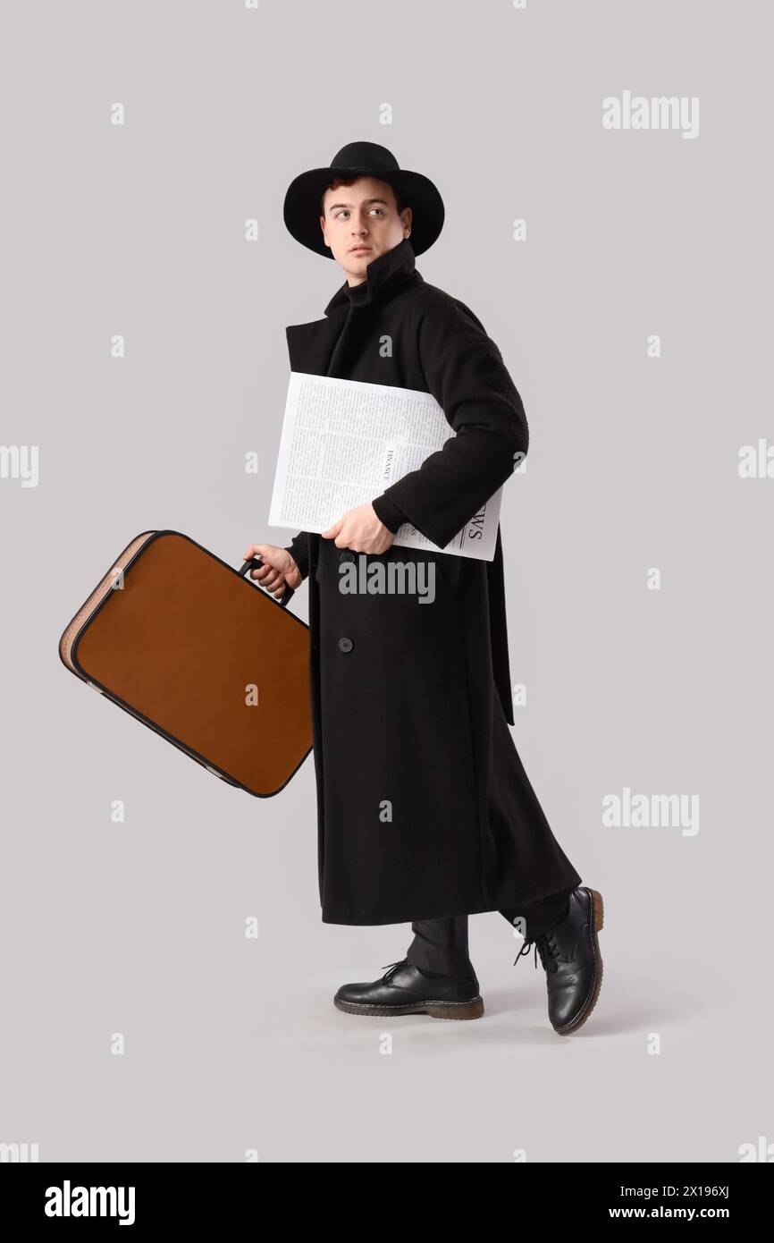 Male spy with newspaper and bag walking on light background Stock Photo ...