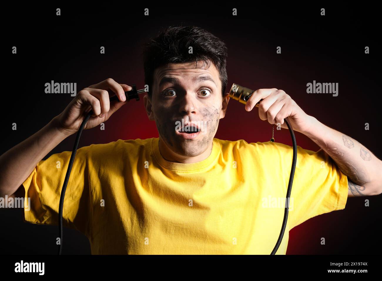 Electrocuted young man with burnt face and plug on dark background ...