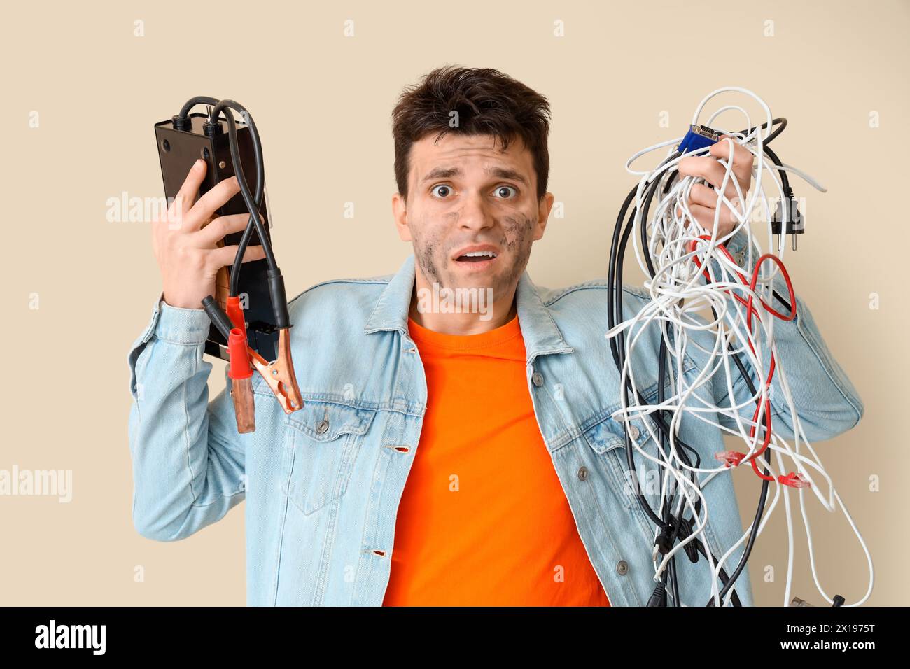 Electrocuted young man with burnt face and wires on beige background ...