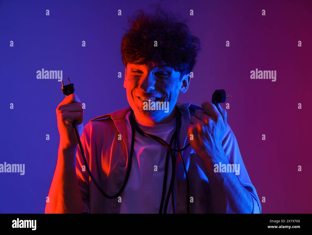 Electrocuted young man with burnt face and plugs on dark background ...