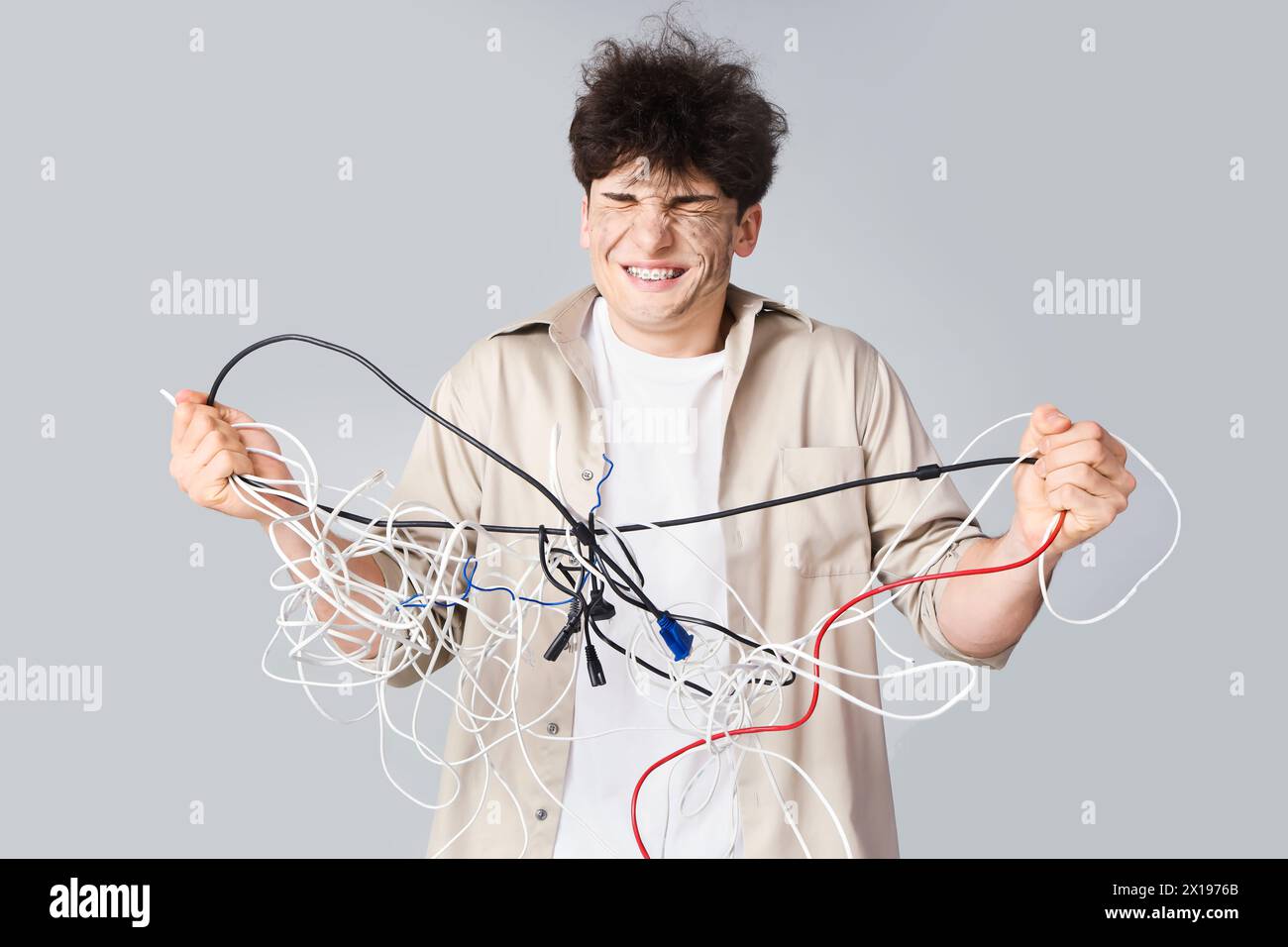 Electrocuted young man with burnt face and wires on light background ...
