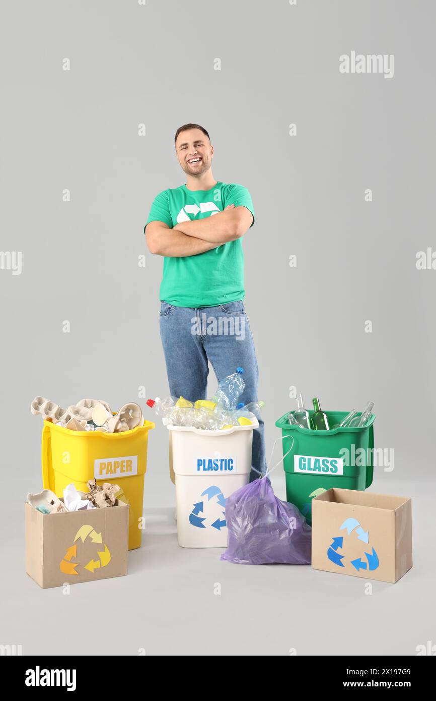 Male volunteer and recycle bins with garbage on light background Stock ...