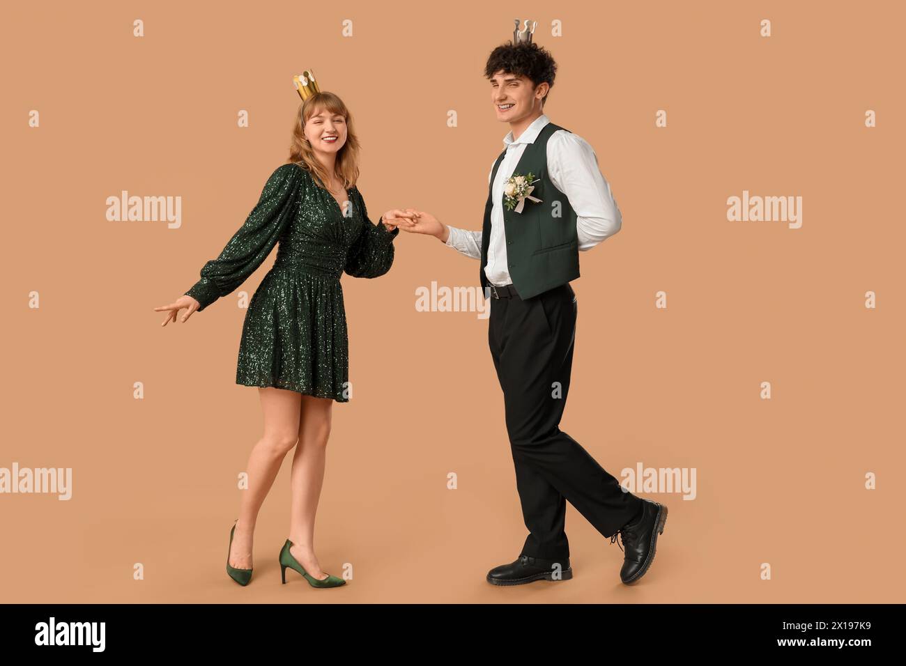 Happy prom couple with crowns dancing on beige background Stock Photo ...