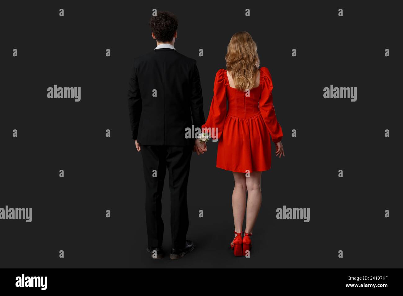Beautiful couple dressed for prom holding hands on black background ...