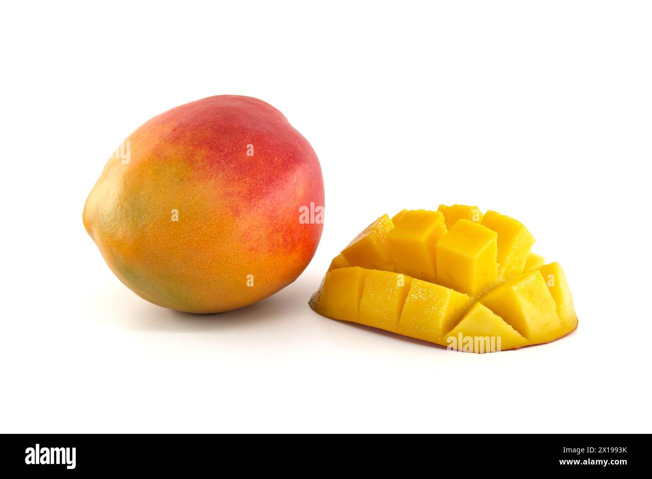 Ripe mango with crimson and yellow skin close to sliced half of a mango ...