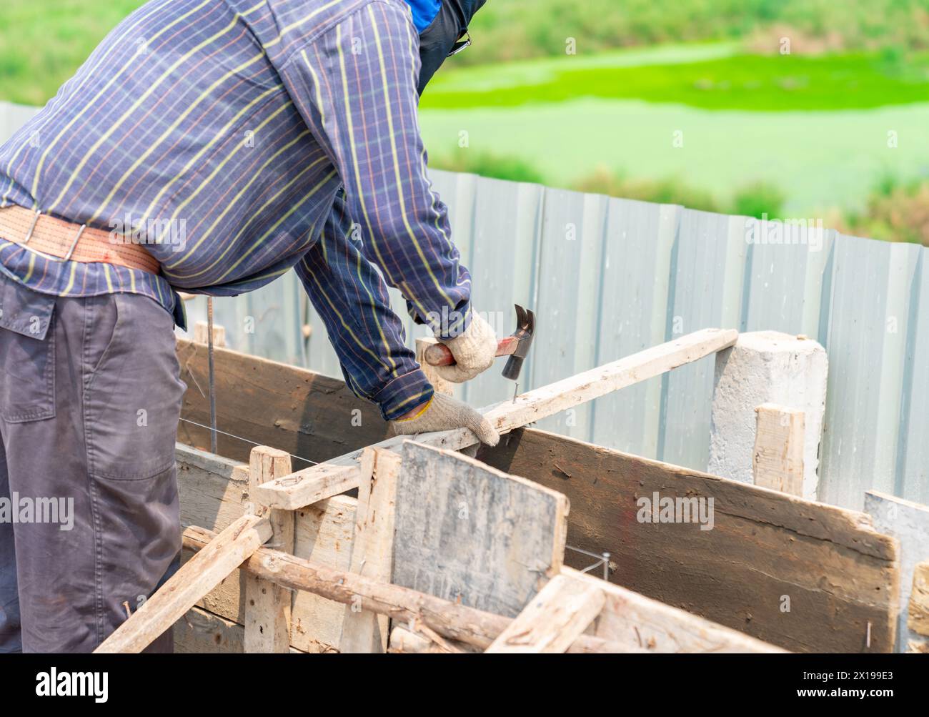 Worker hit nails on wood bar for support formwork in construction site ...