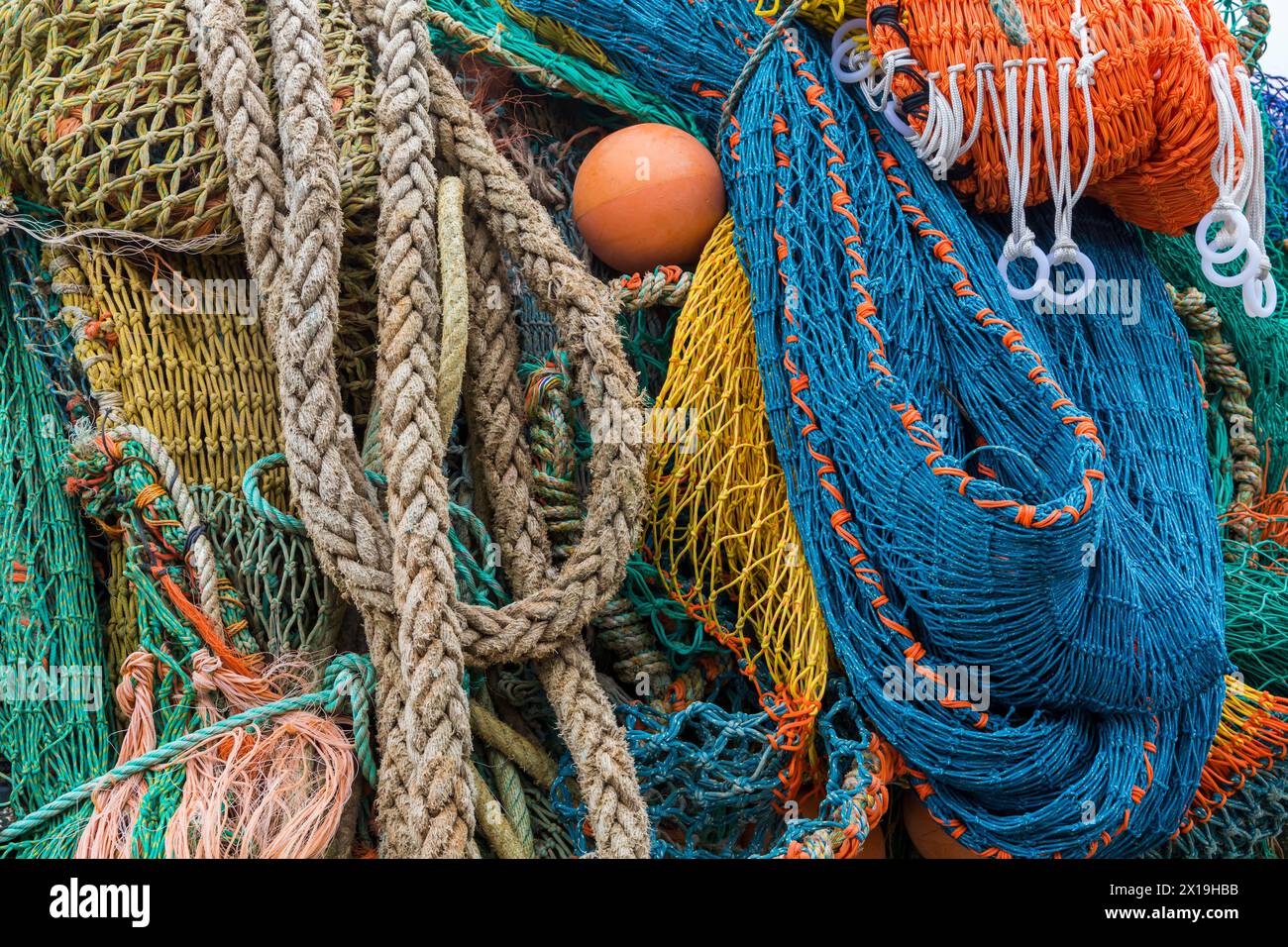 Fishing trawler nets hanging on the quay at Lyme Regis harbour, Dorset ...