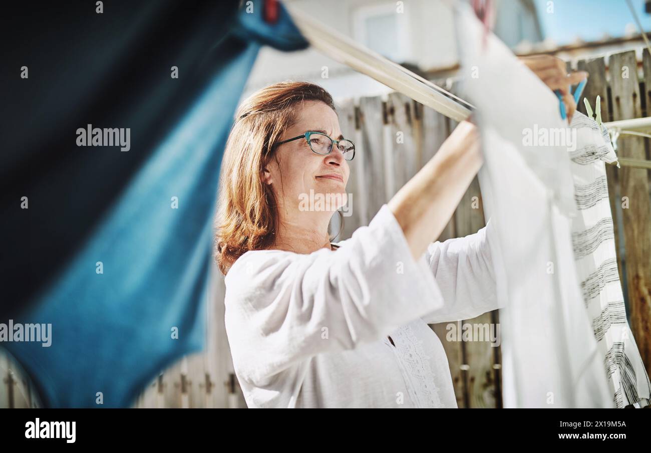 Mature woman, clothesline and laundry outdoor with household domestic ...