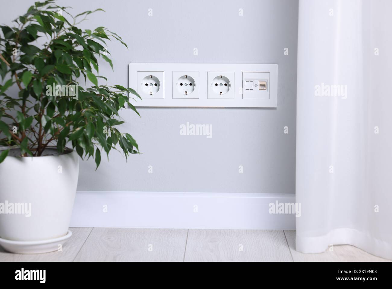 Electric power sockets on light grey wall indoors Stock Photo - Alamy