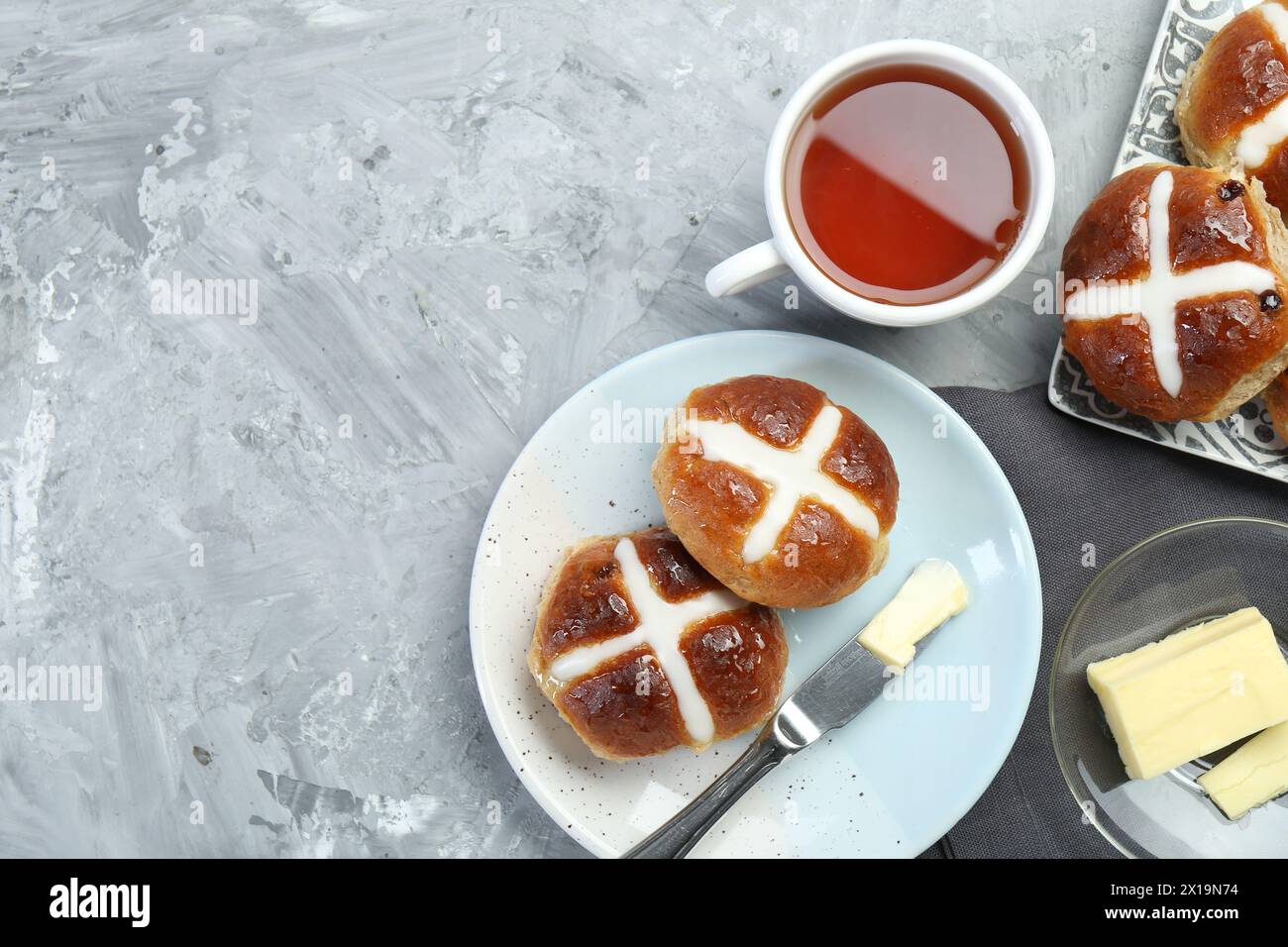 Tasty hot cross buns served on gray textured table, flat lay. Space for ...